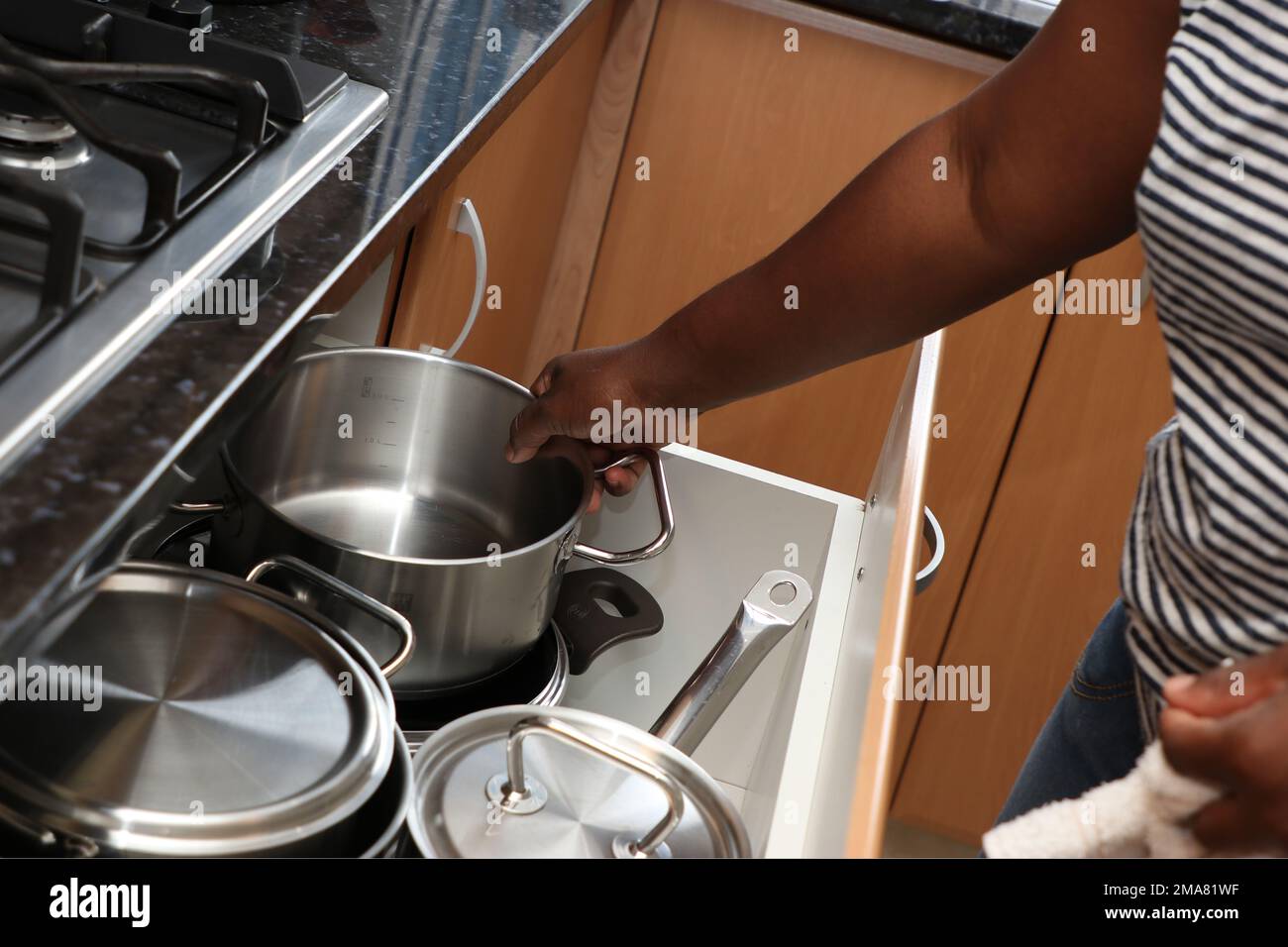 An African lady drying a cooking pot with a dish towel in the kitchen ...