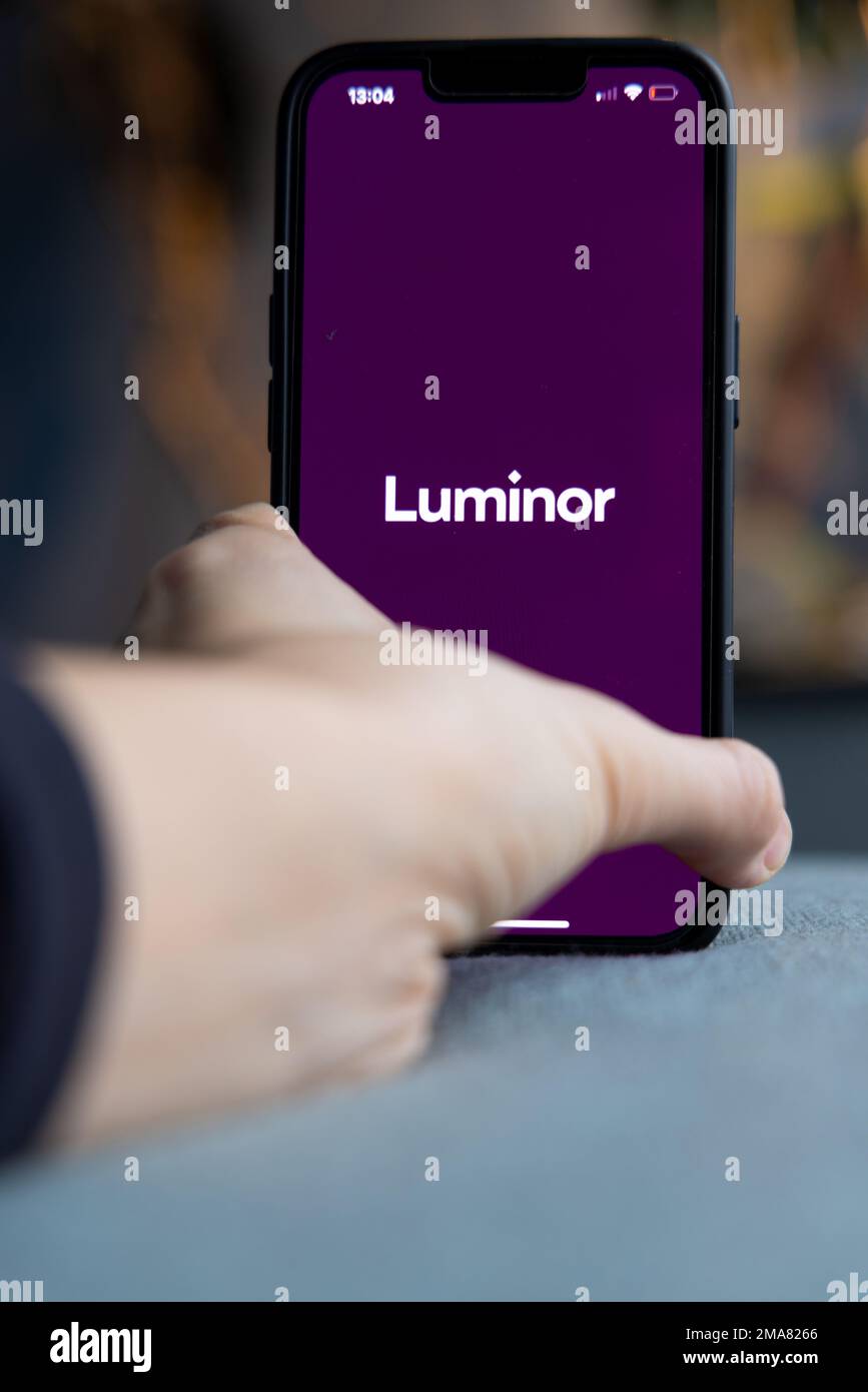 Hand holding a smartphone with Luminor bank icon on screen. White ...