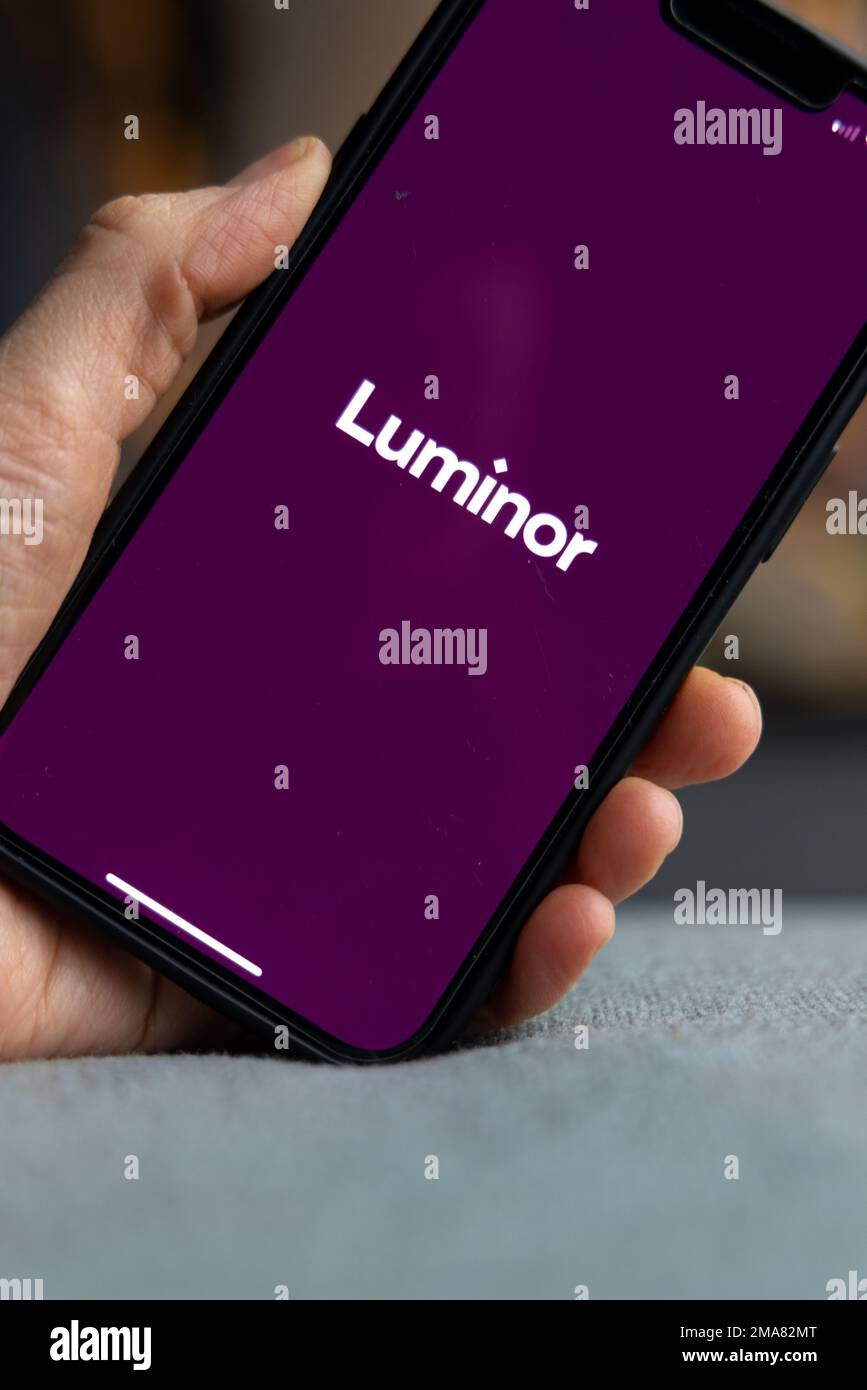 Hand holding a smartphone with Luminor bank icon on screen. White ...
