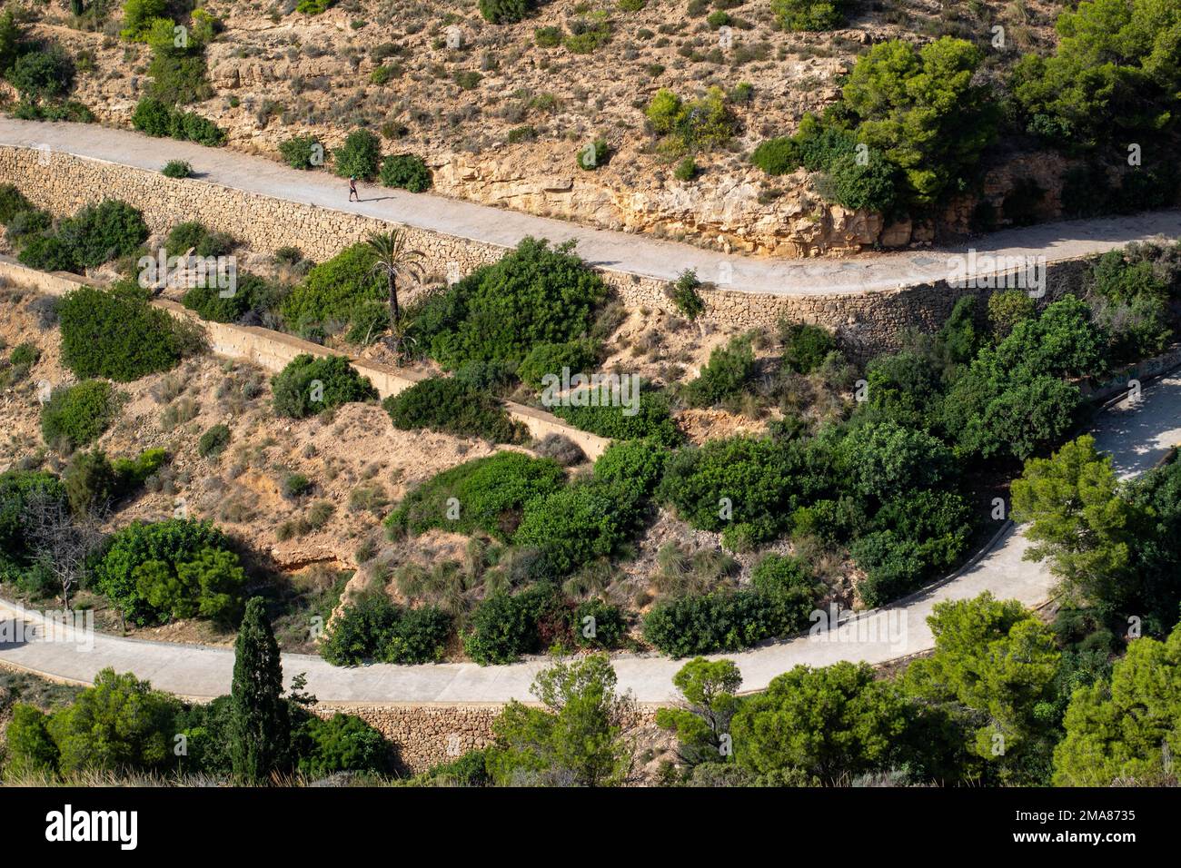An aerial view of a pedestrian walking path through mountains in ...