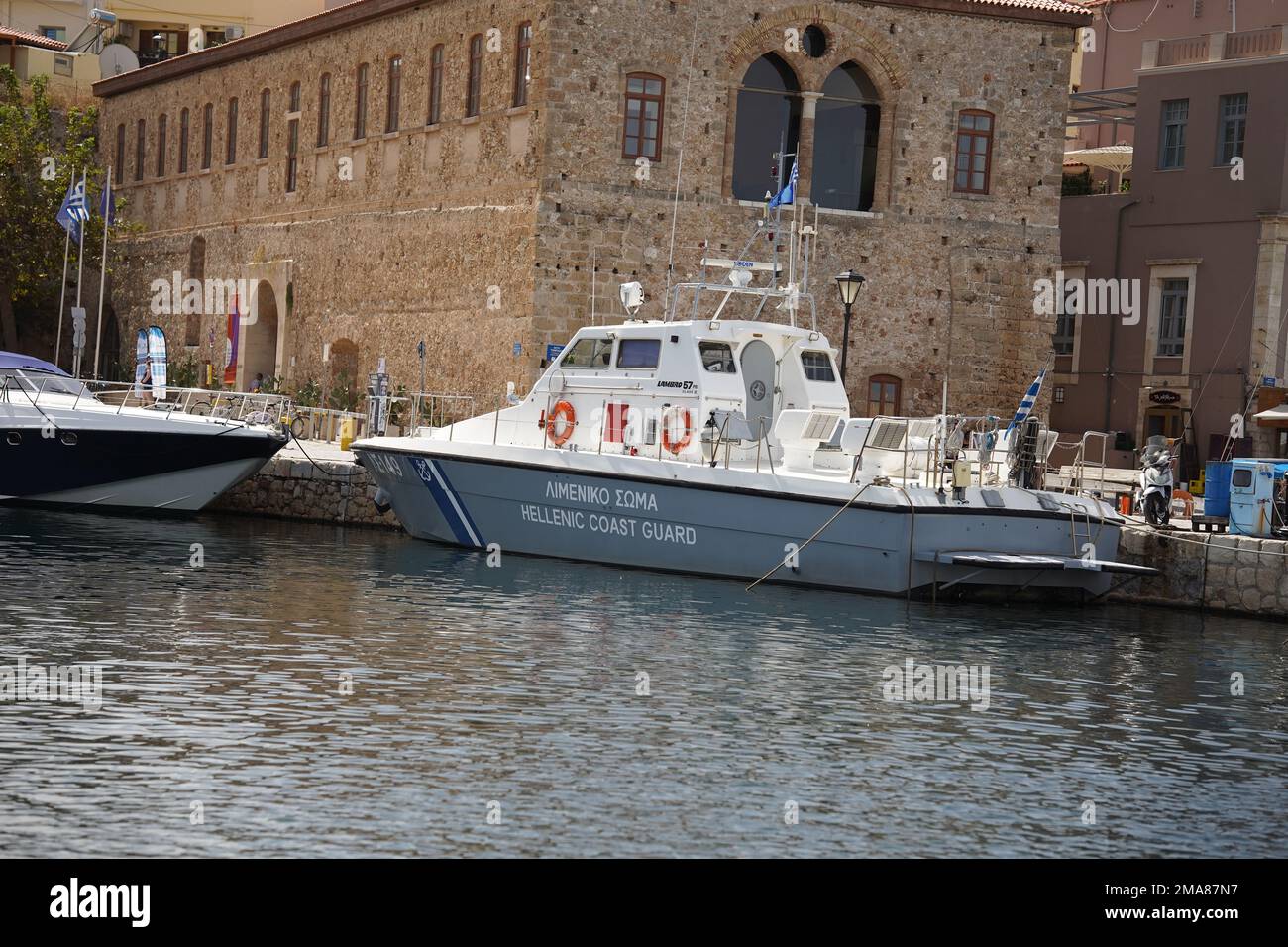 A boat of the Hellenic Coast Guard on the water surrounded by buildings ...