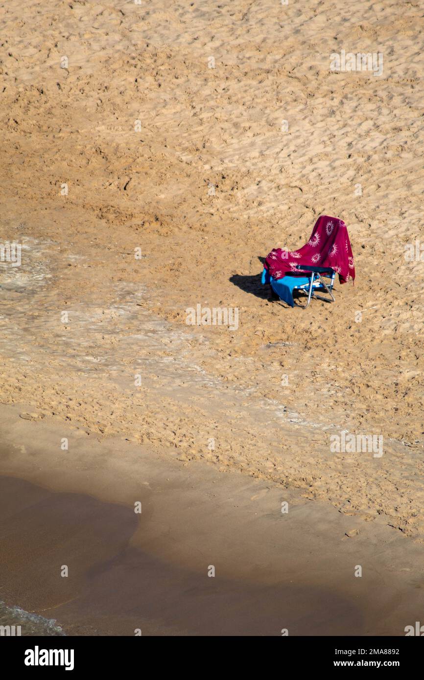A vertical high angle shot of a blue beach chair with a red cover on ...
