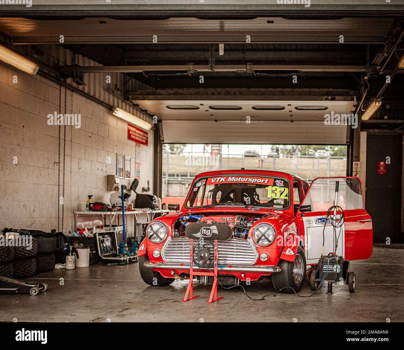 Classic red mini owned by VTK Motorsport being serviced in the pit ...