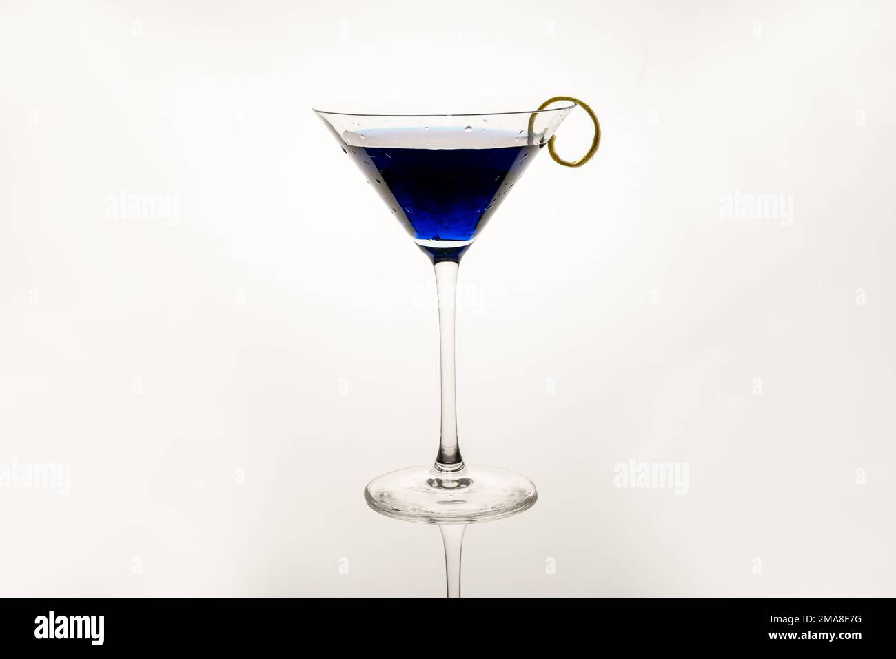 Royal Blue Martini served with a lemon twist isolated on a white ...