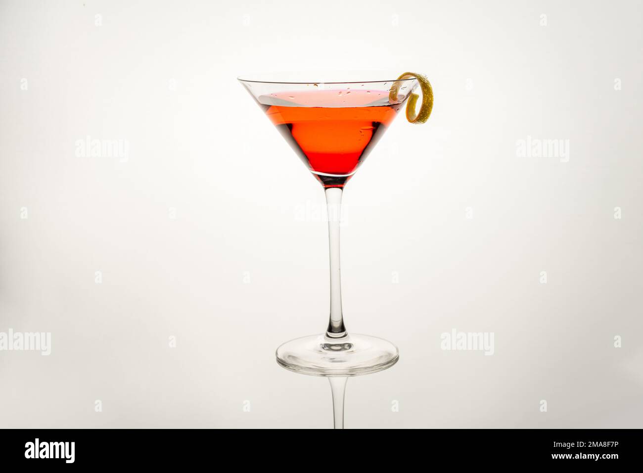 Martini glass with pink lady cocktail, lemon twist isolated on a white ...