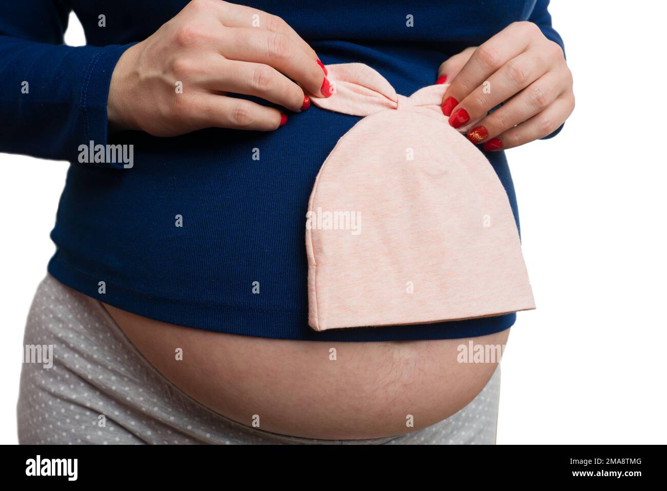 Close-up of future mother holding children pink hat isolated on white ...