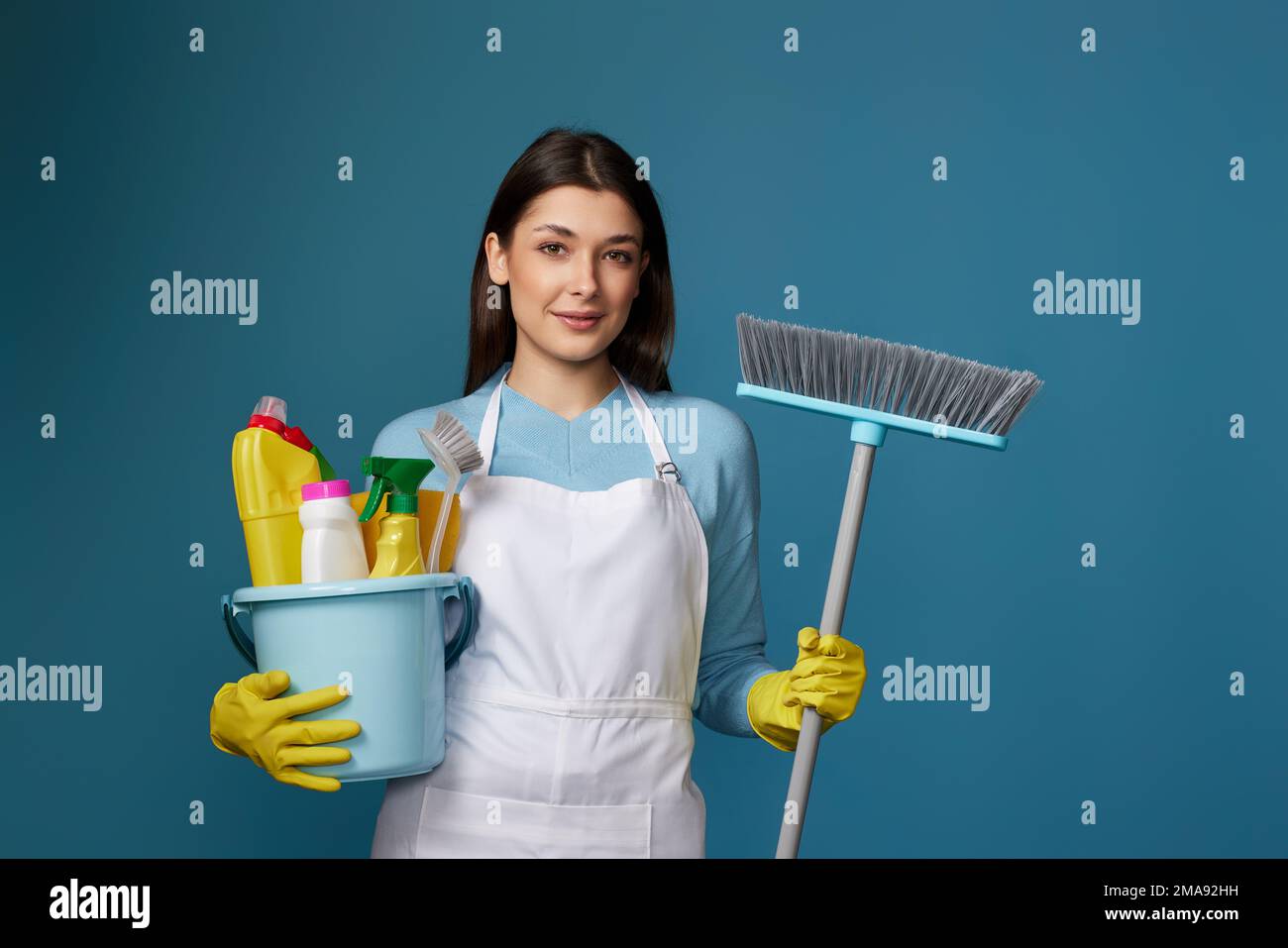 woman in cleaner apron holding bucket of detergents and broom Stock ...