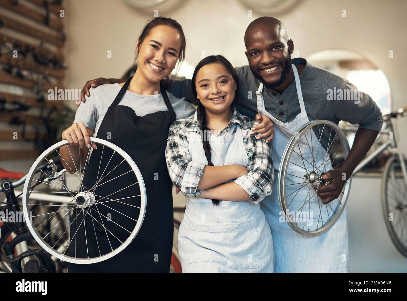 Come inside. Portrait of three young workers at a bicycle repair shop ...