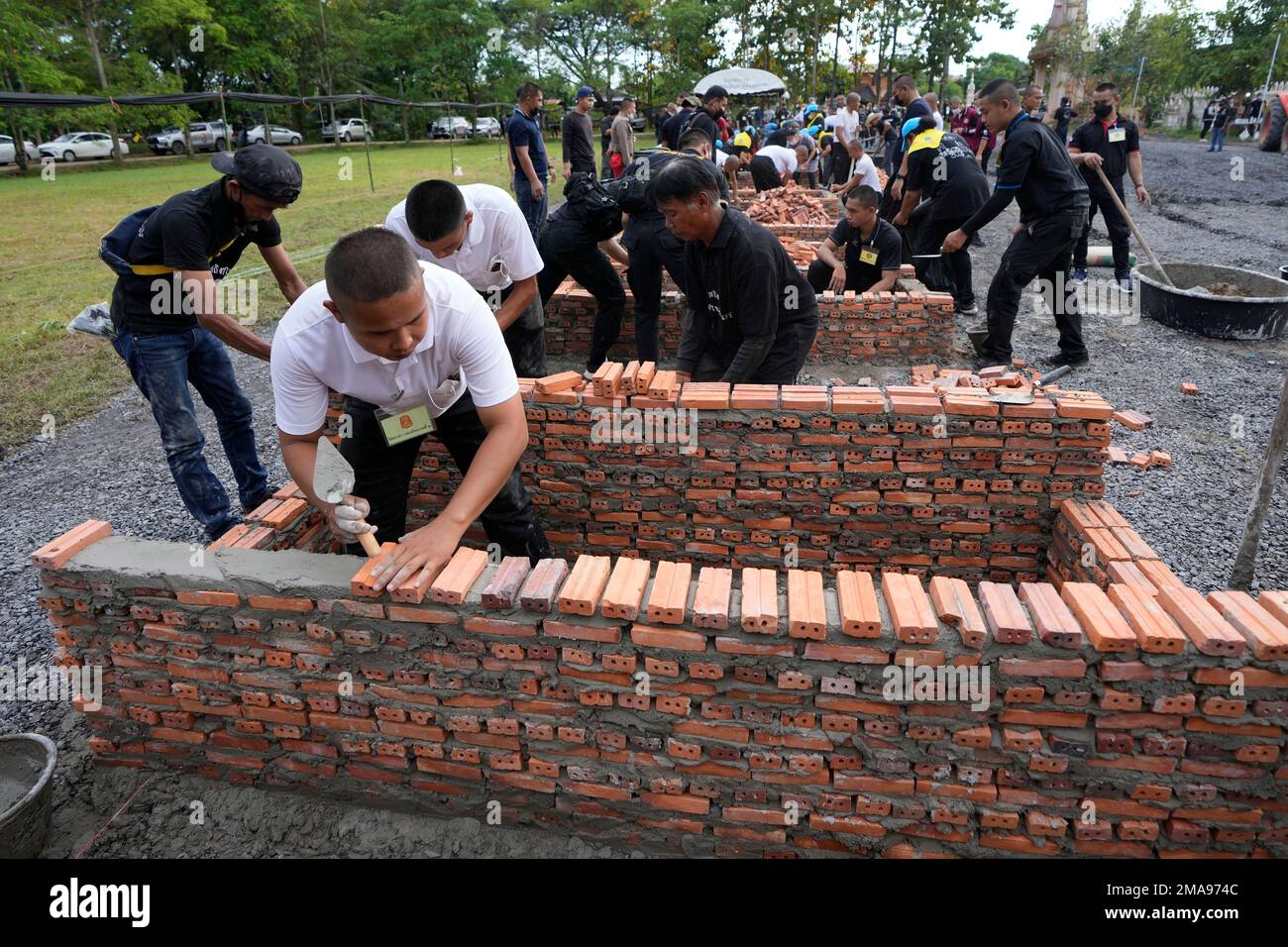 A police officer helps lay bricks for cremation furnaces at Wat Rat ...