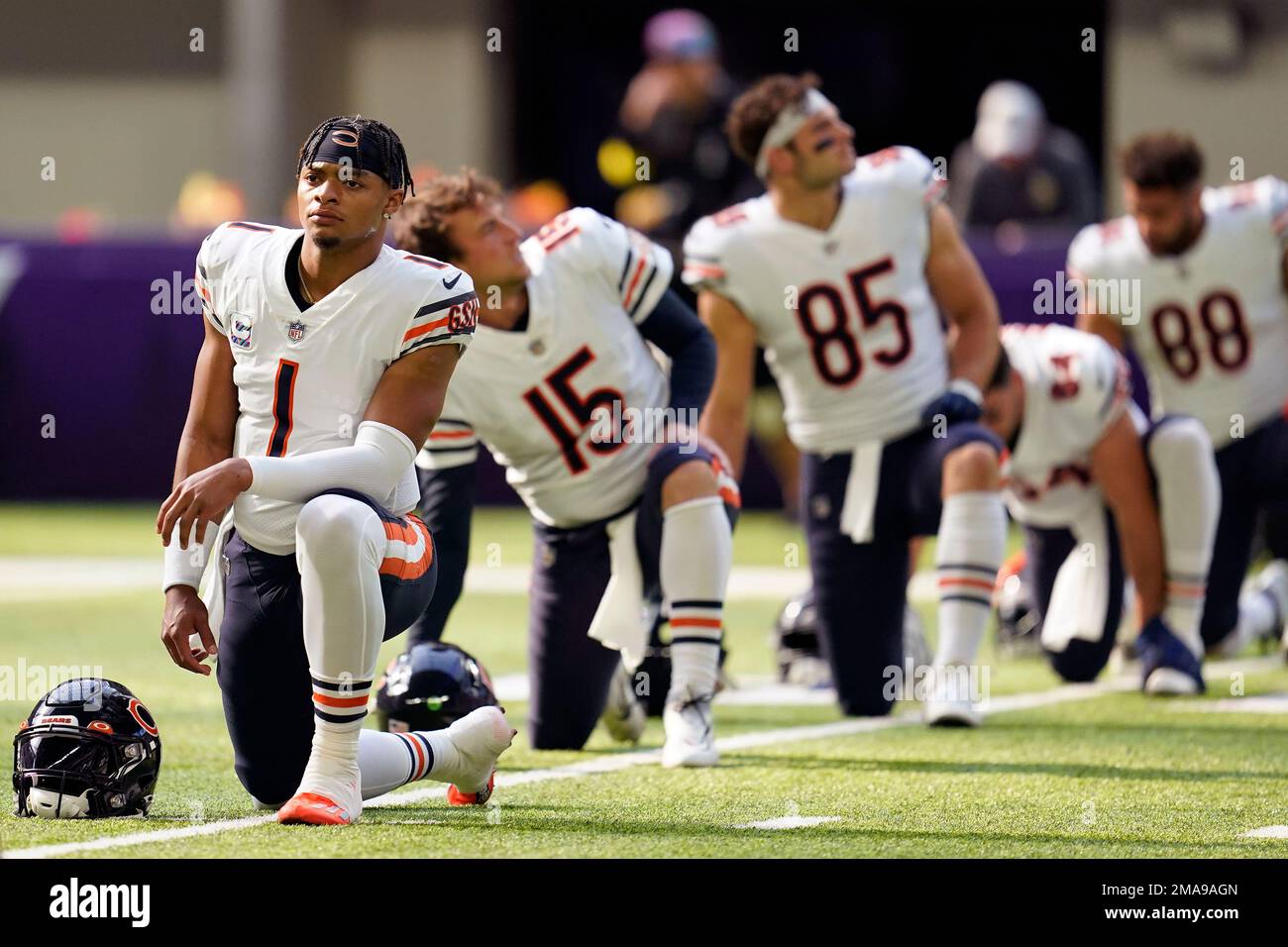 Chicago Bears quarterback Justin Fields (1), left, stretches before an ...