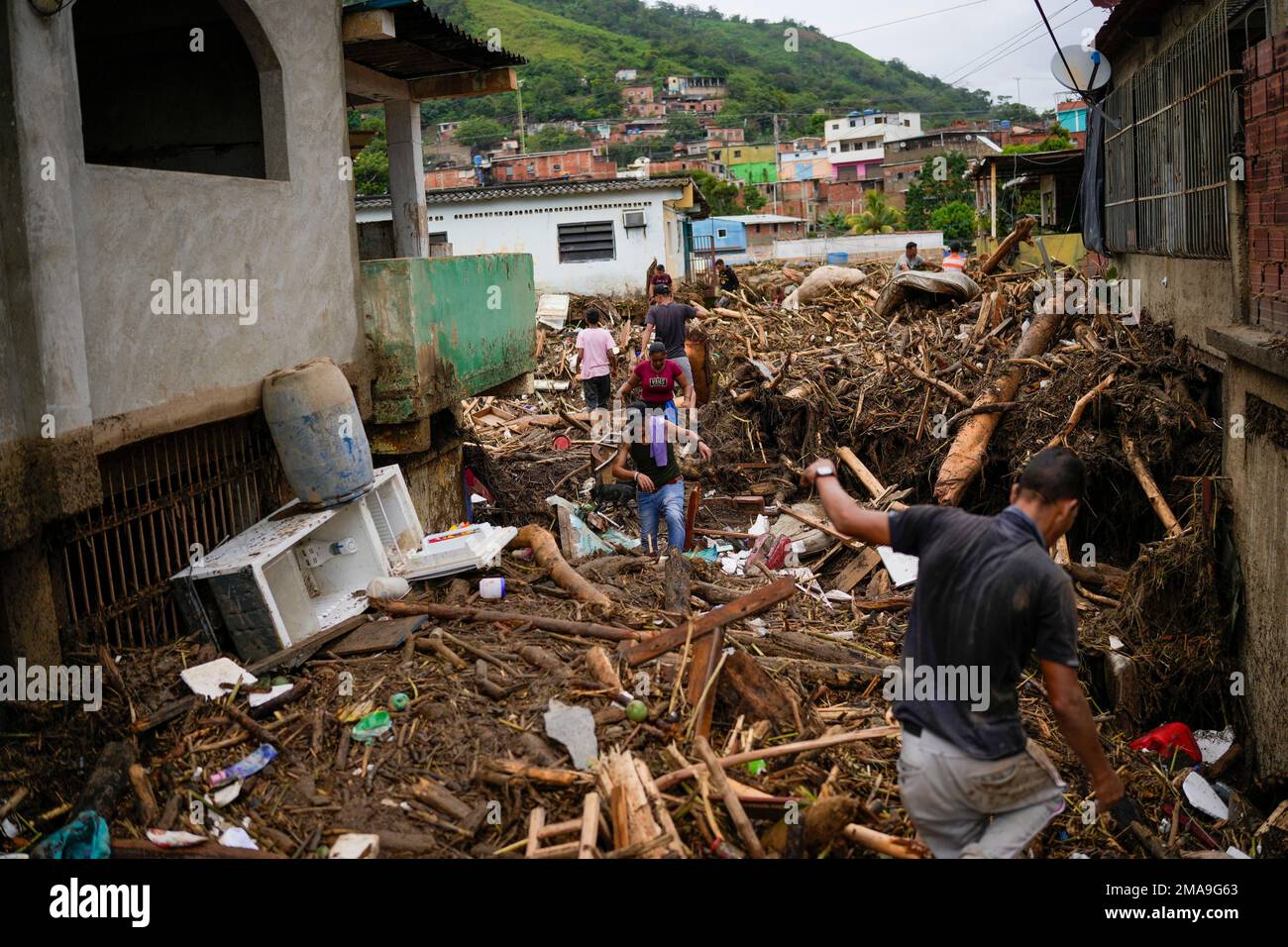 Residents walk through the debris left by flooding caused by a river ...