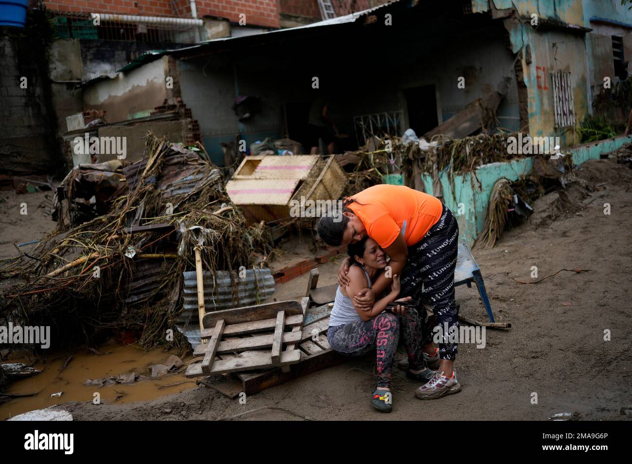 A neighbor, right, comforts a woman crying in front of her damaged home ...