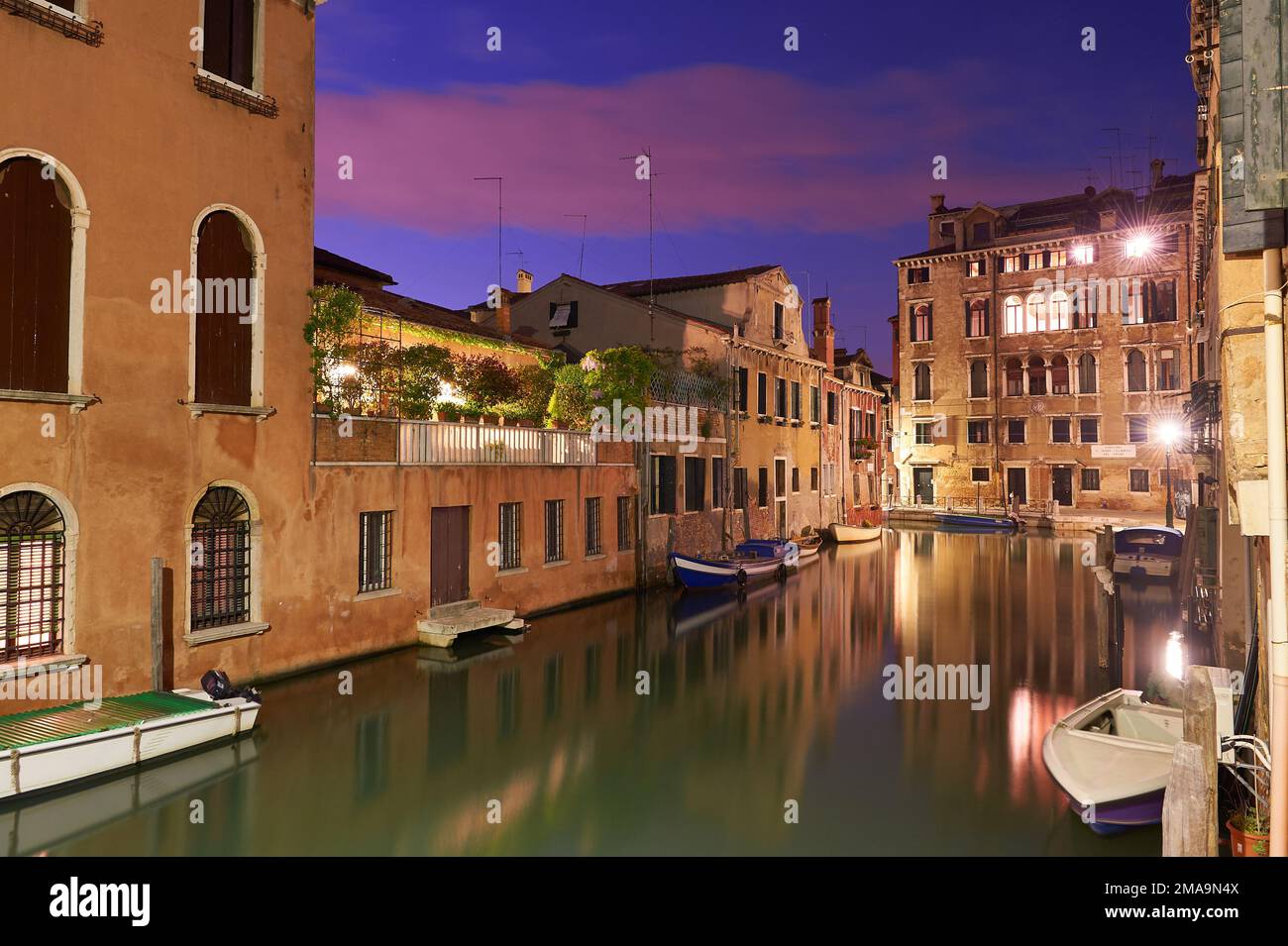The city of Venice at night with a lonely and a little canal and moored ...