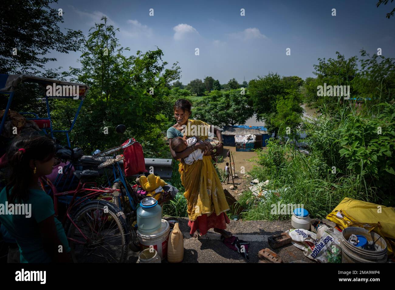 A woman carrying a baby reaches higher ground from her inundated shanty ...