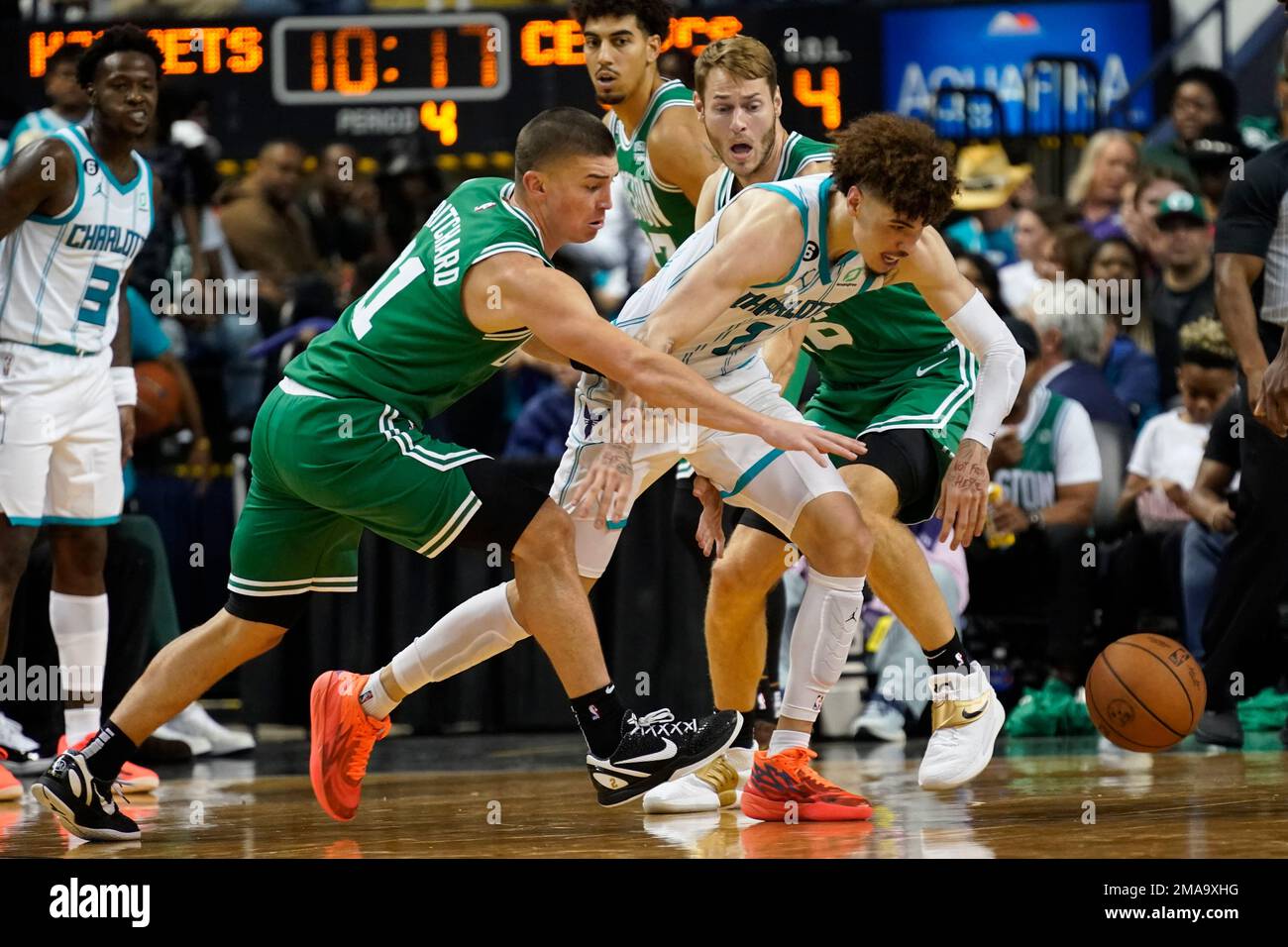 Charlotte Hornets' LaMelo Ball, center, drives between Boston Celtics ...