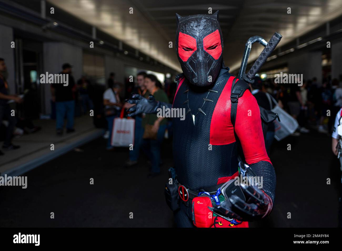 An attendee dressed as a cross between Deadpool and Black Panther poses ...