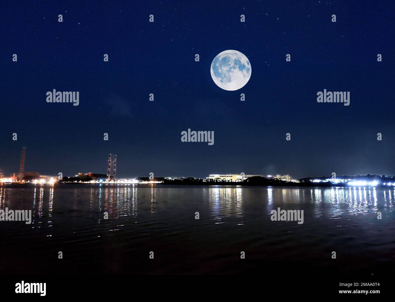 A beautiful full moon in the night sky over a waterscape and urban ...