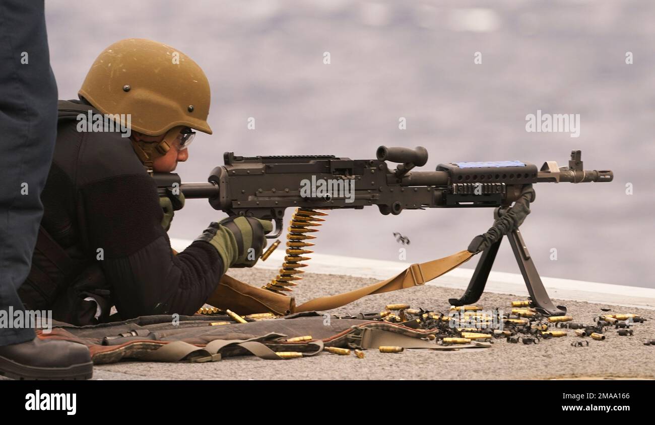 A weapons officers fires a machine gun during a live fire drill aboard ...