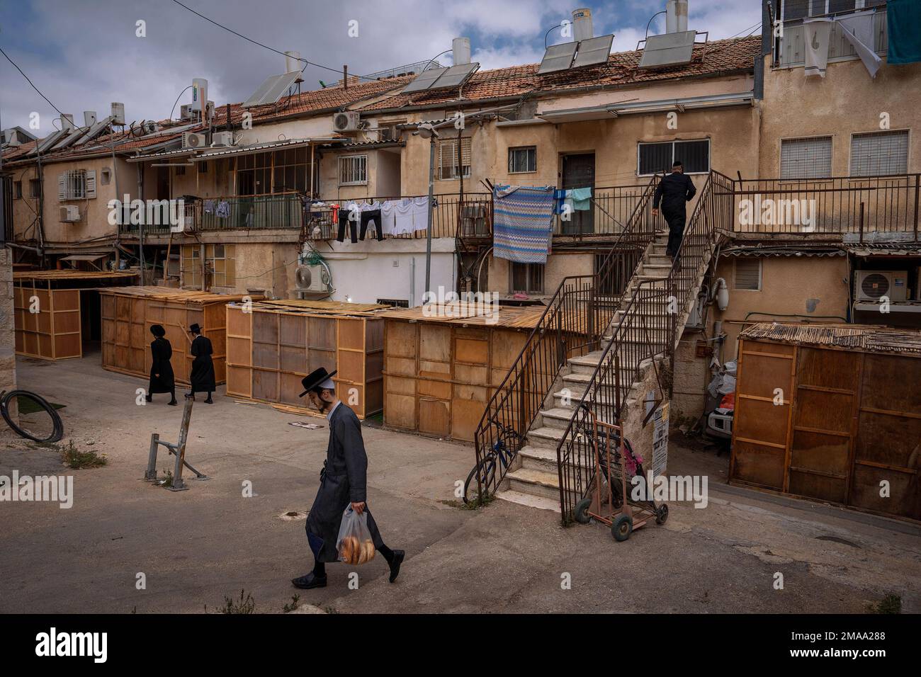Ultra-Orthodox Jews walk by Sukkah, a temporary structure built for the ...