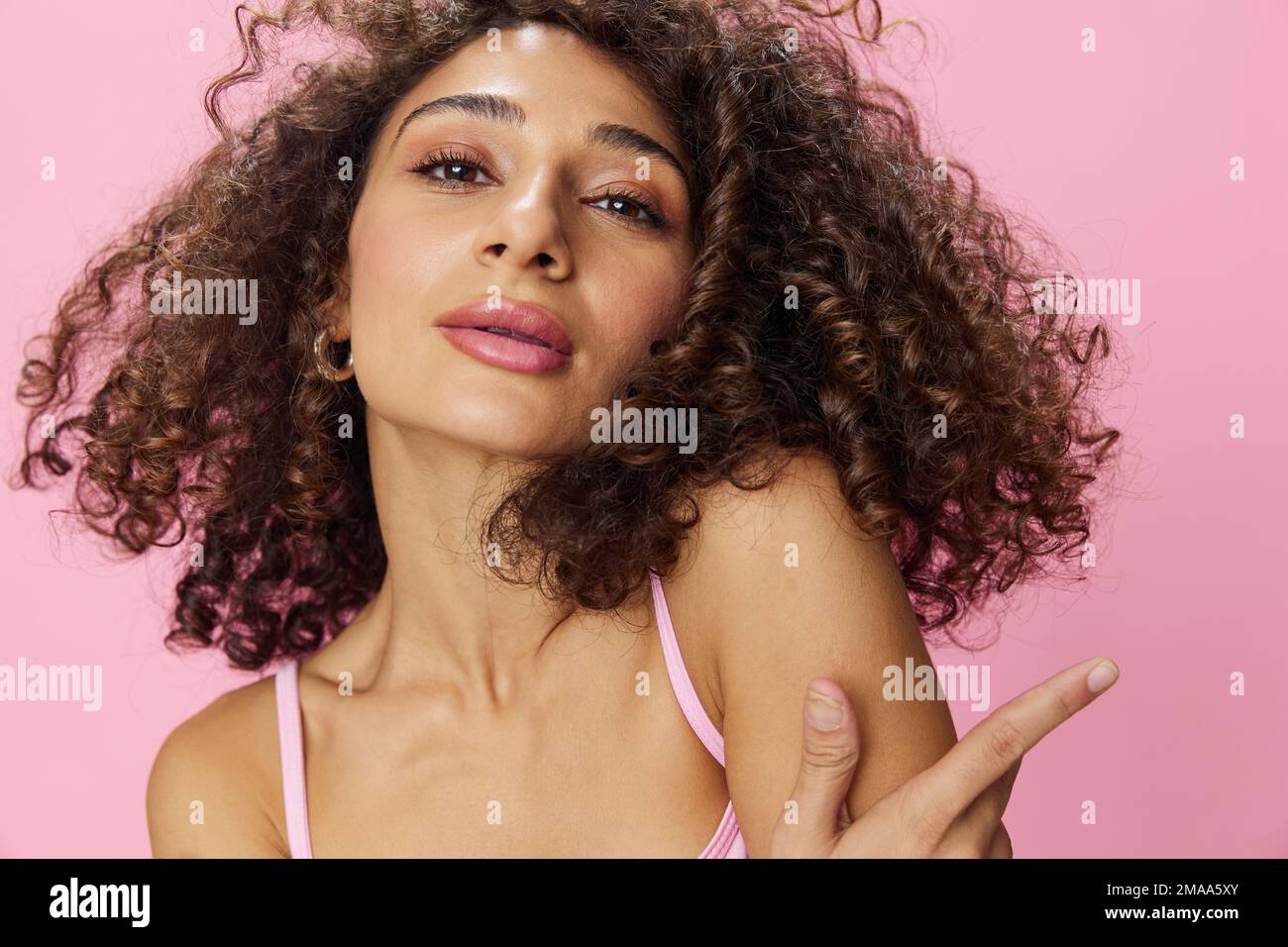 Woman with curly afro hair model poses on a pink background in a pink T ...