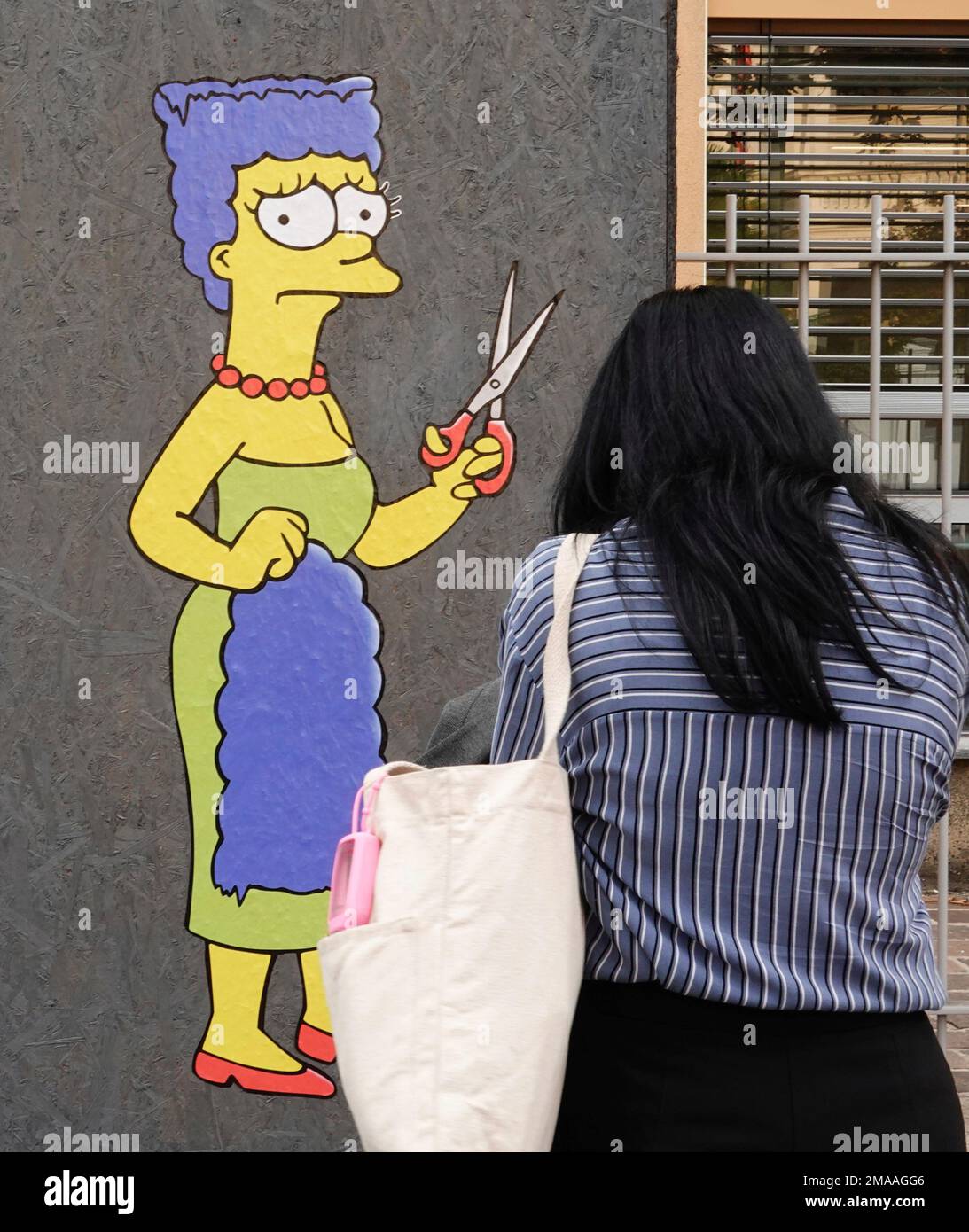 A woman takes pictures of a mural called "The Cut" by street artist ...
