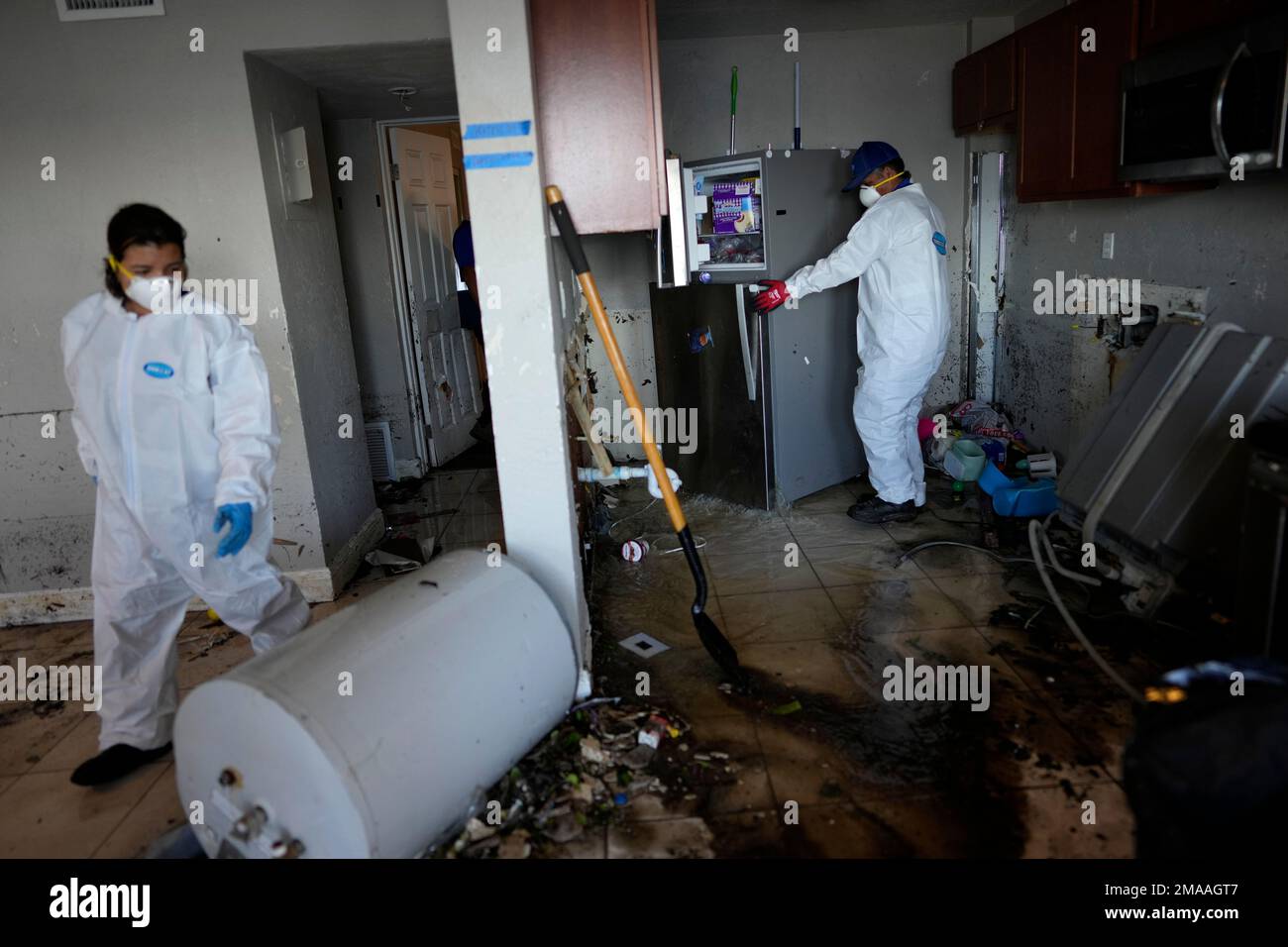 A worker releases flood water from the refrigerator after standing it ...