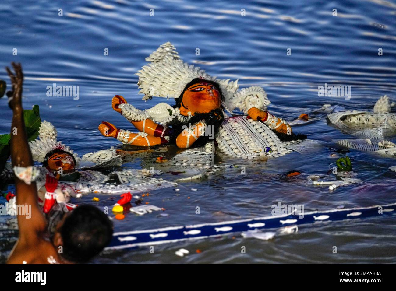A man pushes an idol of Hindu goddess Durga towards deeper water after ...