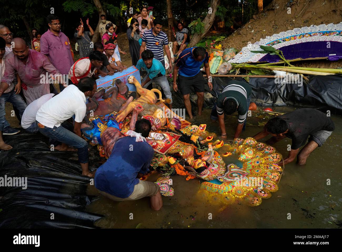 Devotees immerse an idol of Hindu Goddess Durga in a makeshift pond at ...