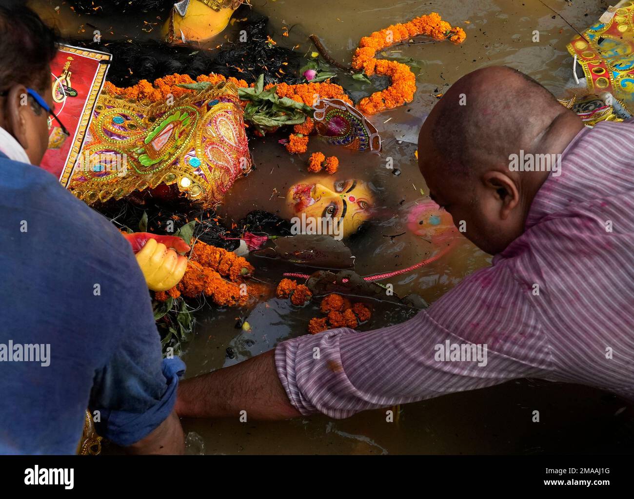 Devotees immerse an idol of Hindu Goddess Durga in a makeshift pond at ...