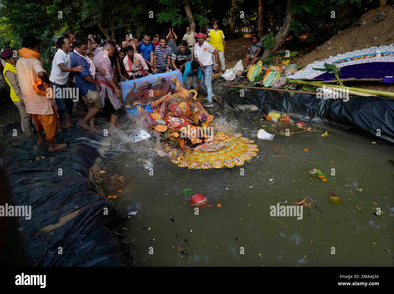Devotees immerse an idol of Hindu Goddess Durga in a makeshift pond at ...