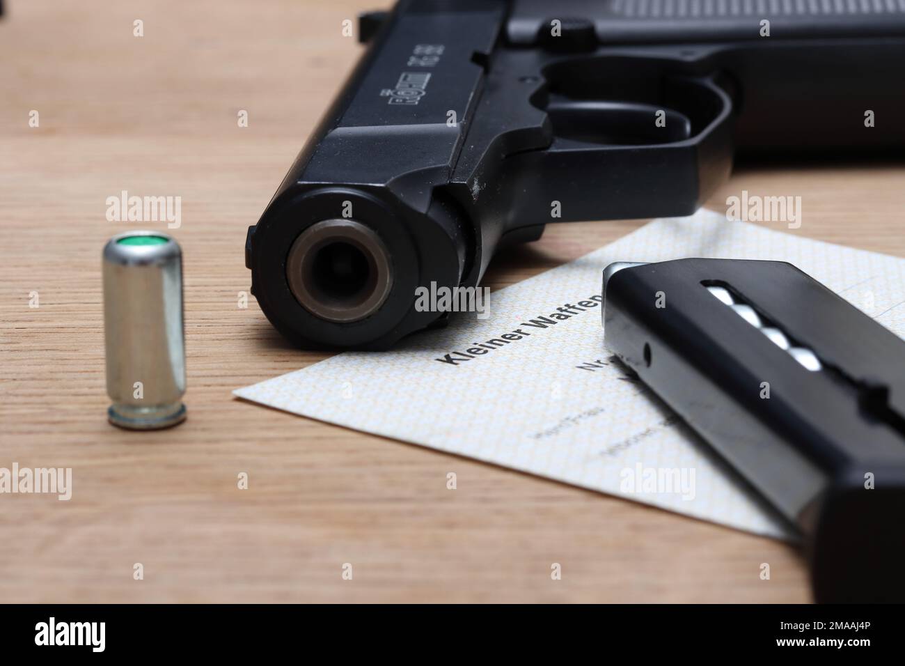 A closeup shot of a small black Rohm brand pistol, ammunition, and a ...