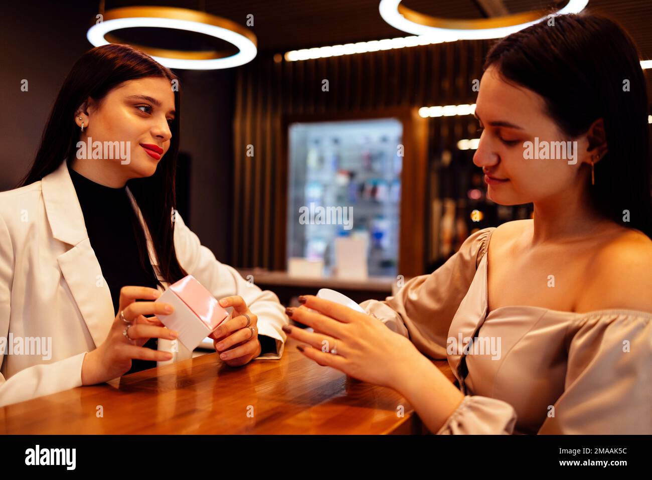 Young female receptionist working in beauty salon and offers cosmetics ...