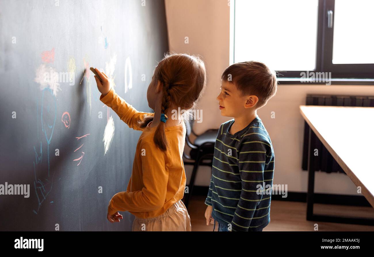 Cute little girl and boy drawing with crayon color on the wall. Works ...