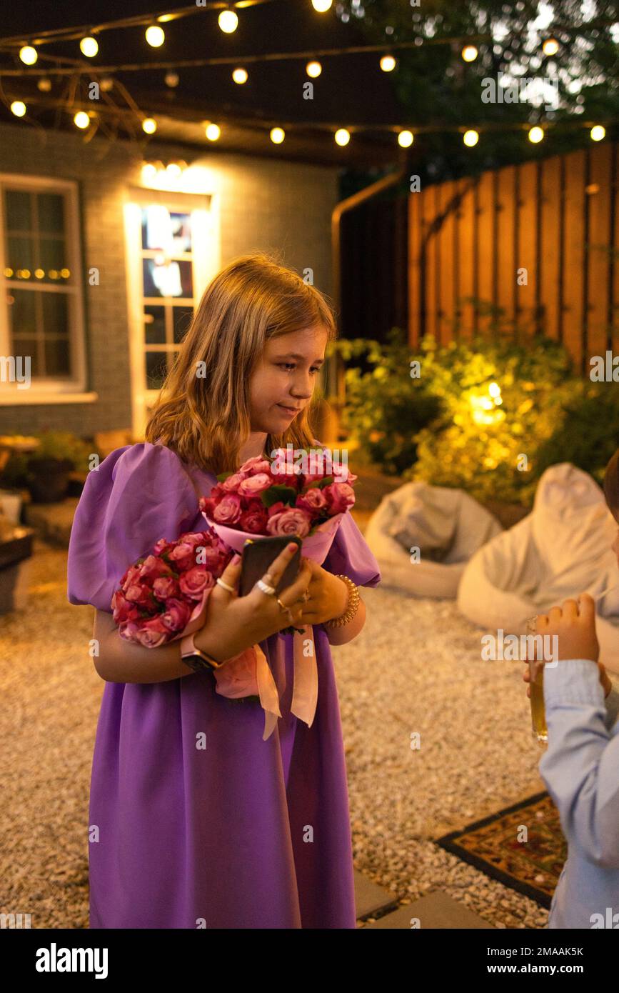 Cute teen girl with rose flowers. Child playing in summer garden. Kids ...