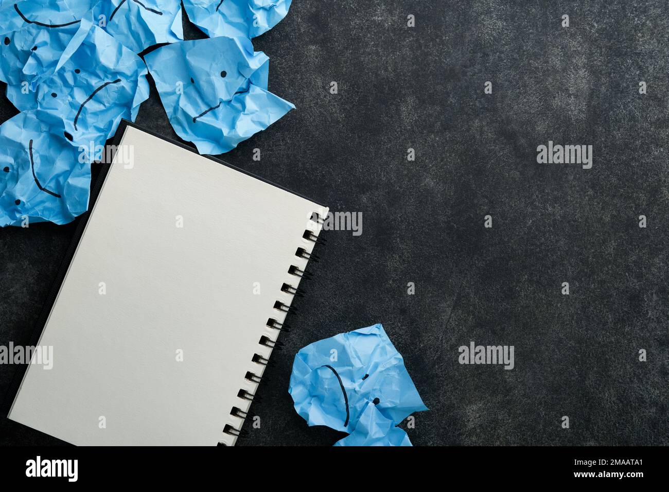 Blue crumpled sticky notes blank with drawing sad face on black ...