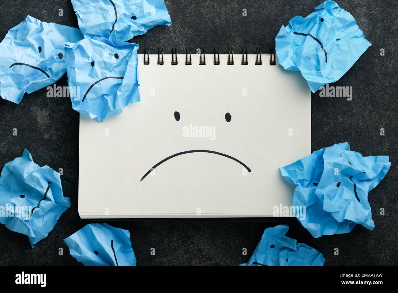 Blue crumpled sticky notes blank with drawing sad face on black ...