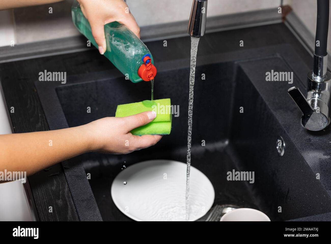 Woman uses dishwashing detergent for wash up dishes in the kitchen at ...