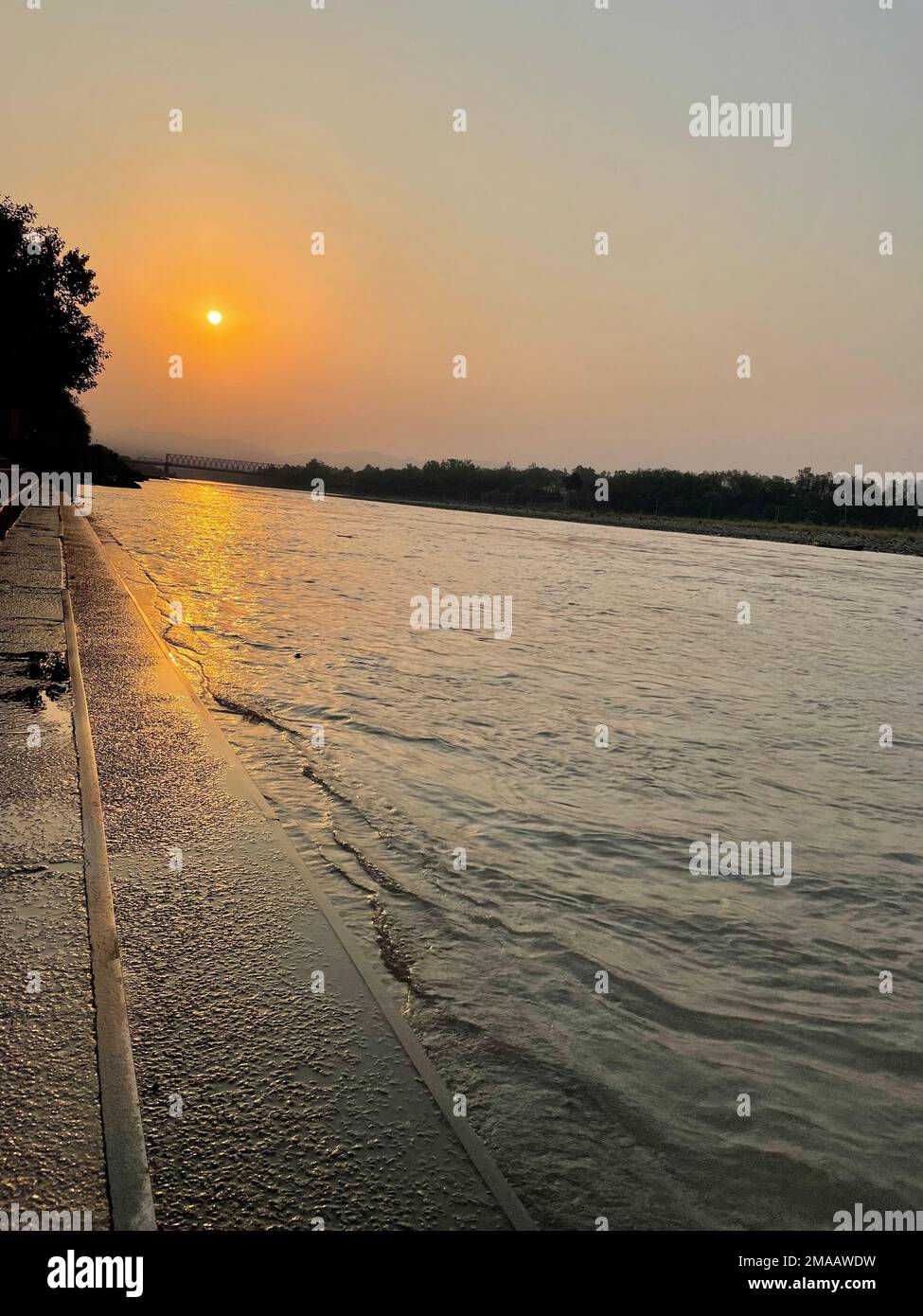 A vertical shot of a golden sunset reflected on a river Stock Photo - Alamy