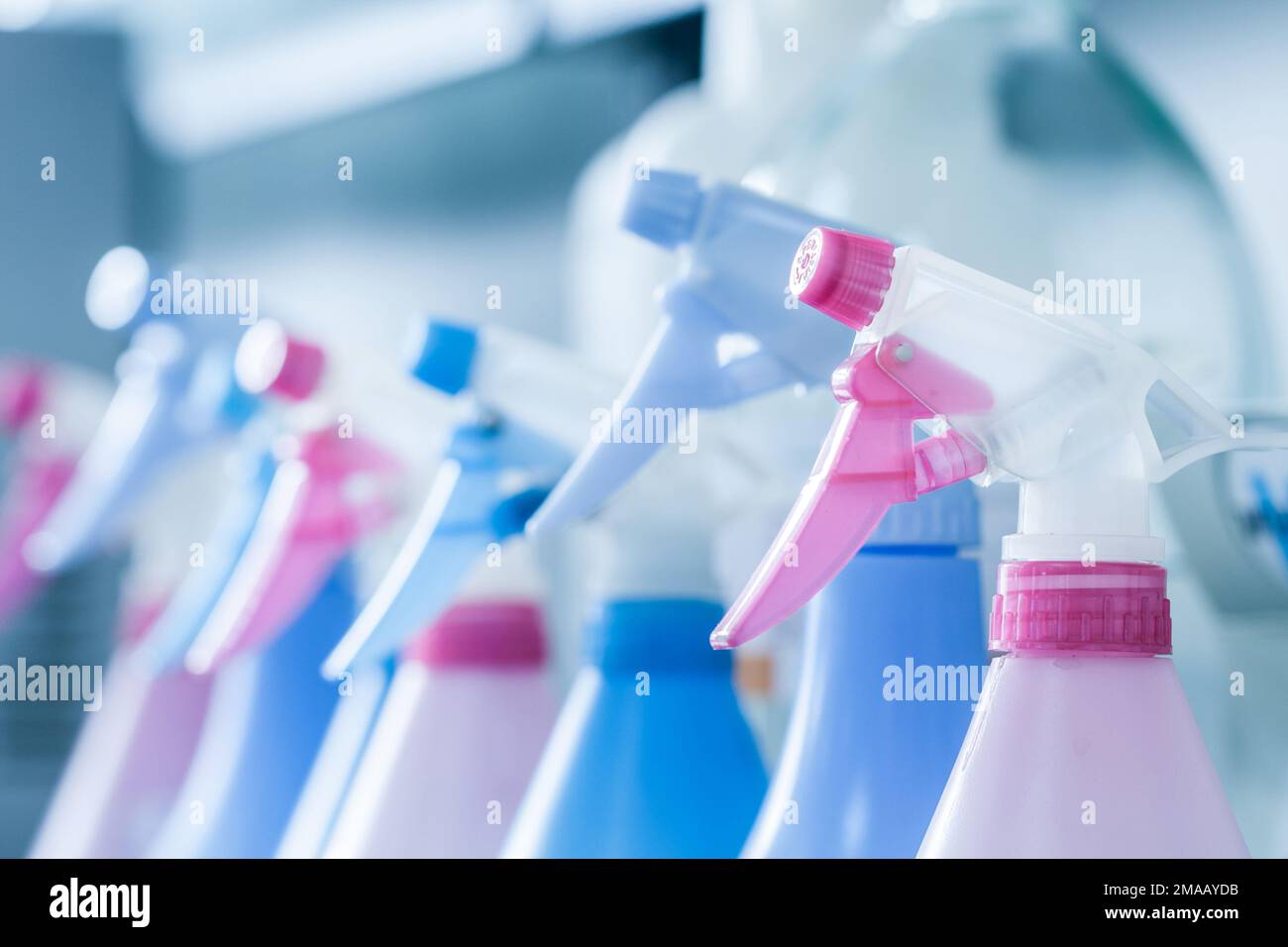 A closeup of pink and blue plastic spray bottles on a shelf in a ...