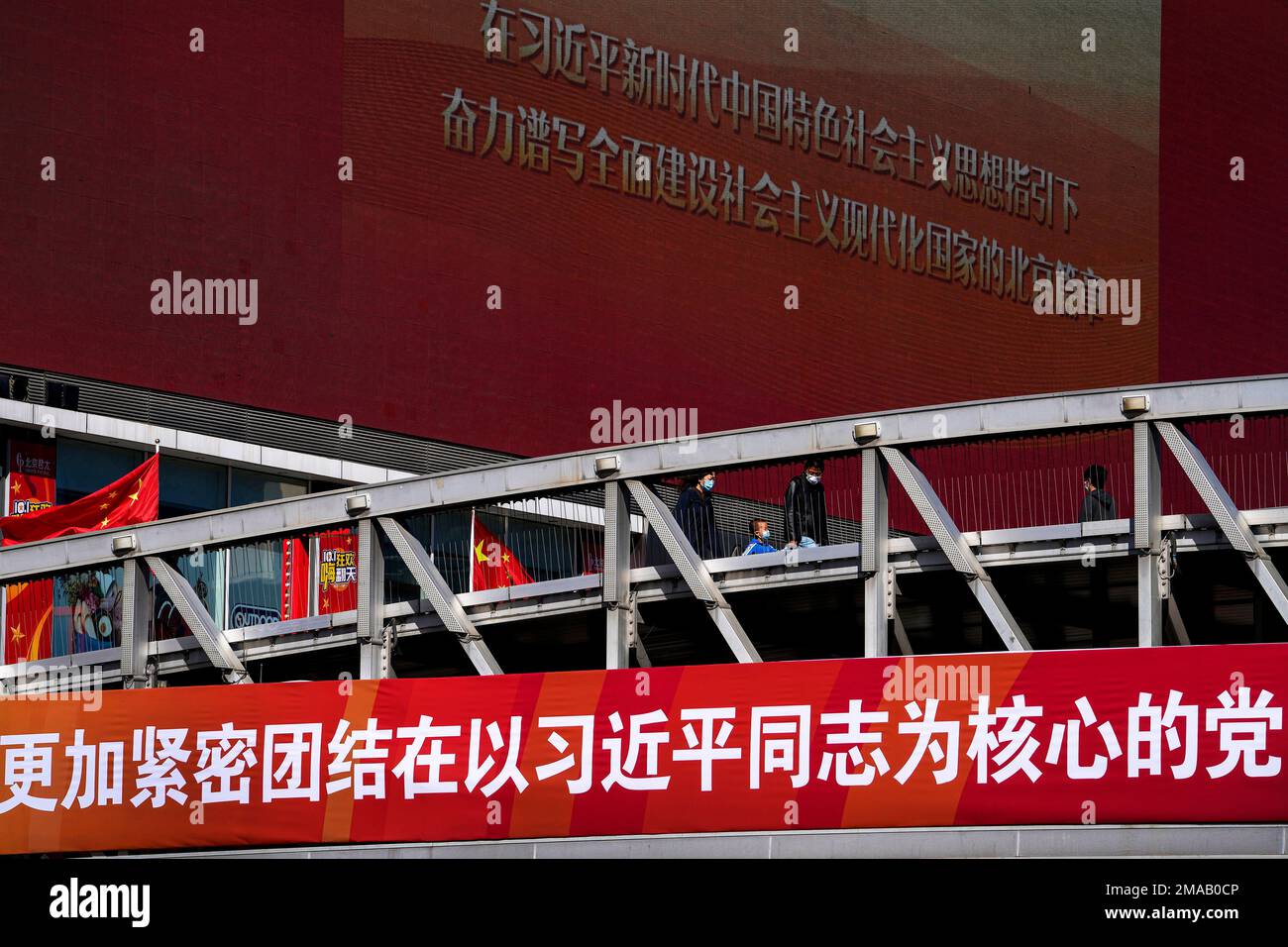 A family wearing face masks walks along a pedestrian bridge against a ...