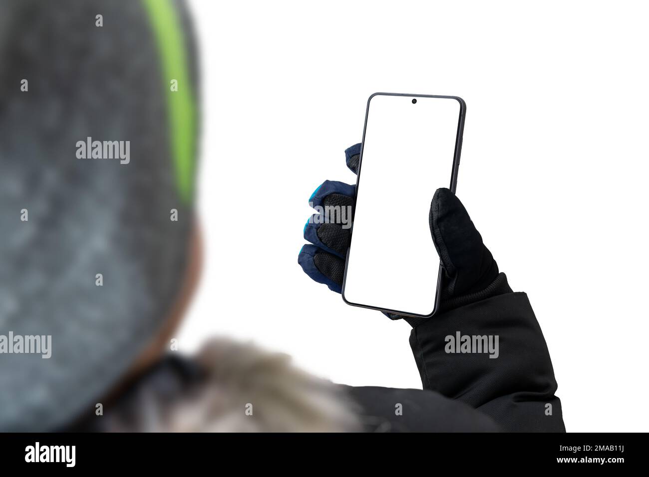 Guy in a jacket with a cap and gloves is holding a mobile phone. The ...