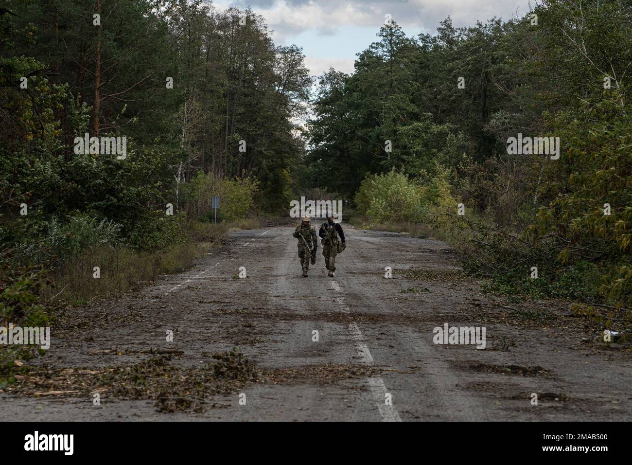 Ukrainian servicemen walk along road while they search for dead bodies ...
