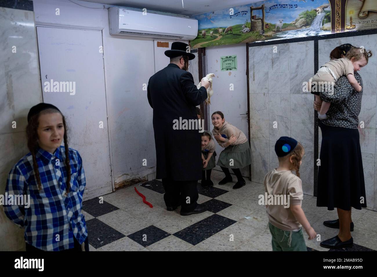 An ultra-Orthodox Jewish man swings a chicken over his kids heads as ...