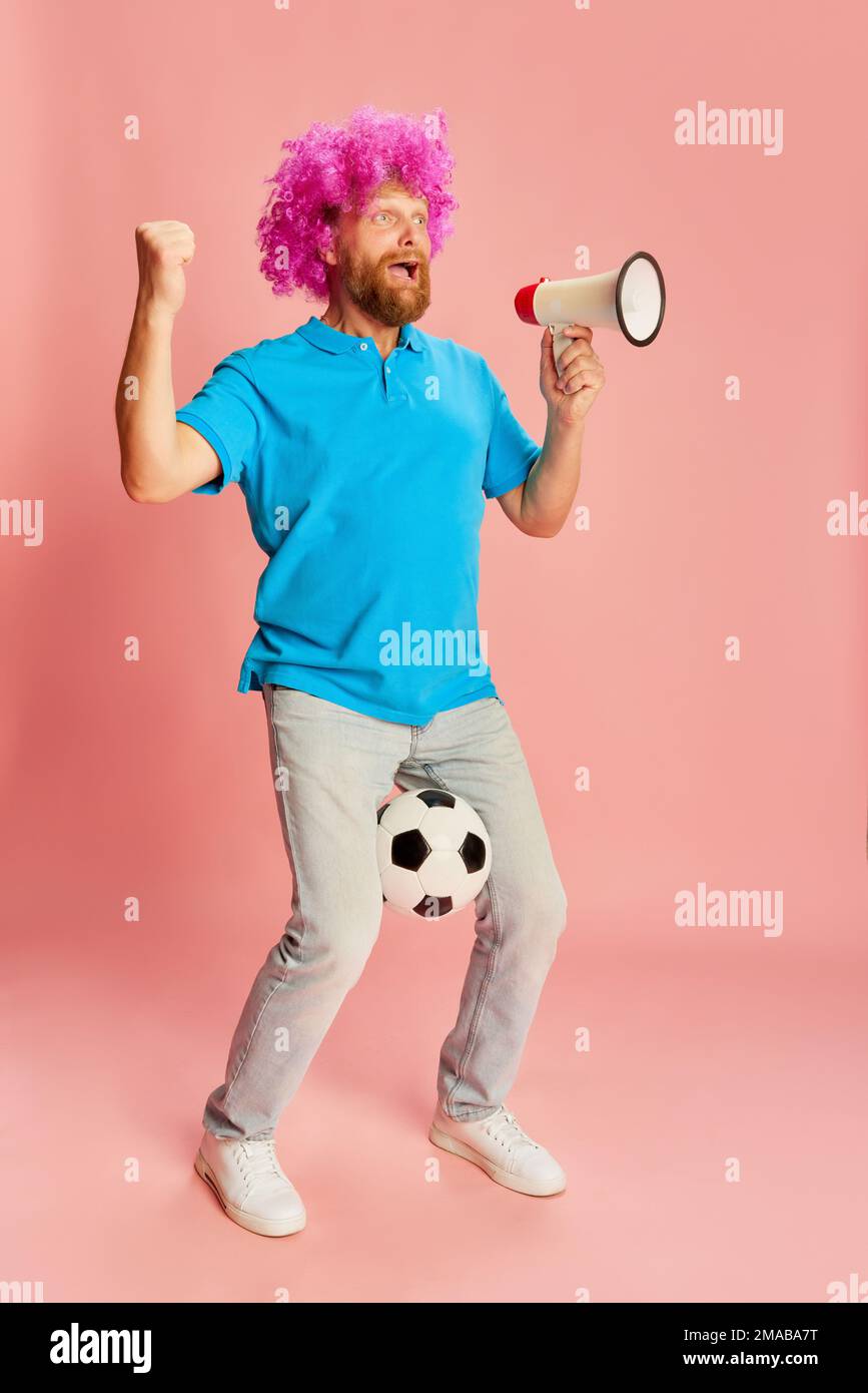 Emotional football fan, young caucasian man in funny wig watching ...
