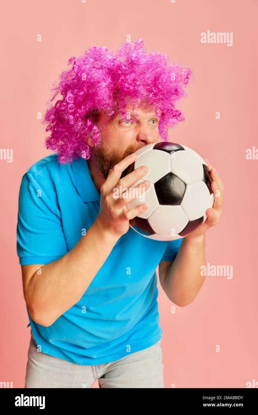 Emotional football fan, young caucasian man in funny wig watching ...