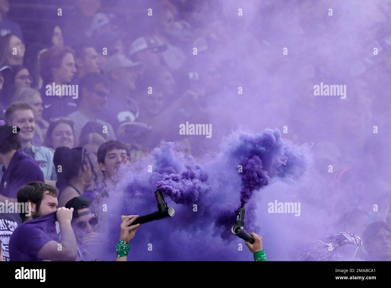 Fans hold up purple smoke devices during the first half of an NCAA ...