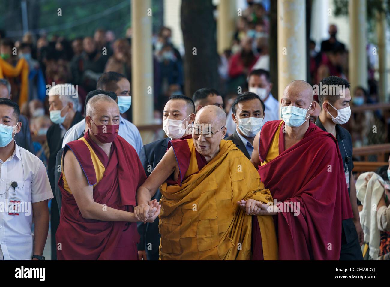 Tibetan spiritual leader the Dalai Lama, in yellow robe, is helped by ...