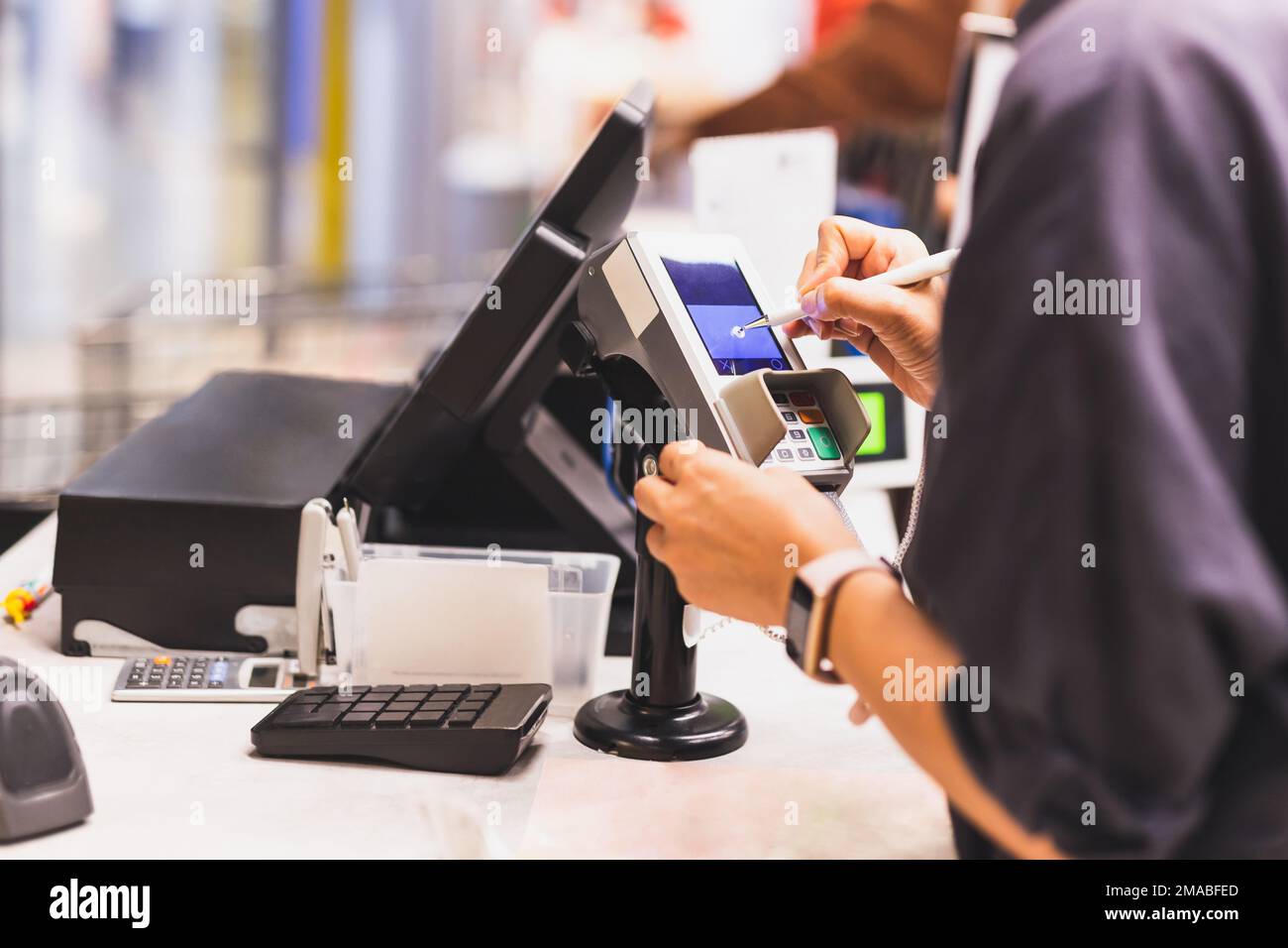 Consumer's women signing on a touch screen of credit card sale ...