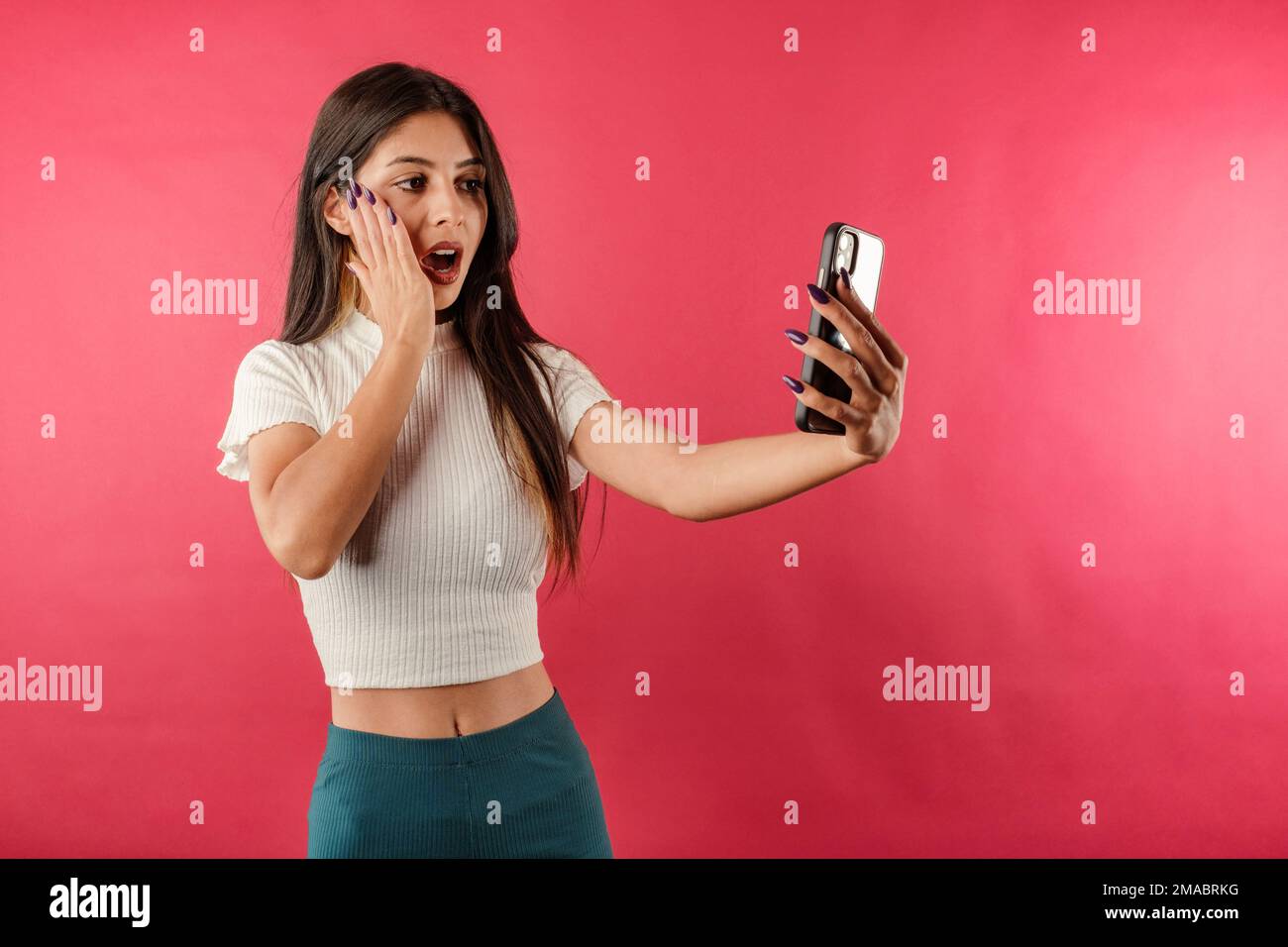 Beautiful brunette woman wearing white ribbed crop isolated over red ...