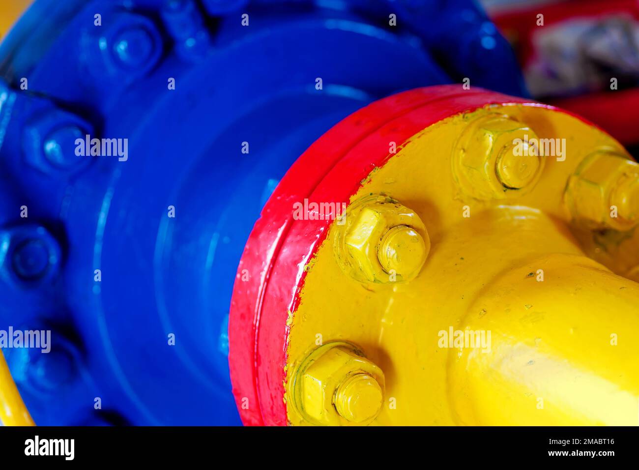 Two blue and yellow gas pipes are connected by large bolts and nuts ...